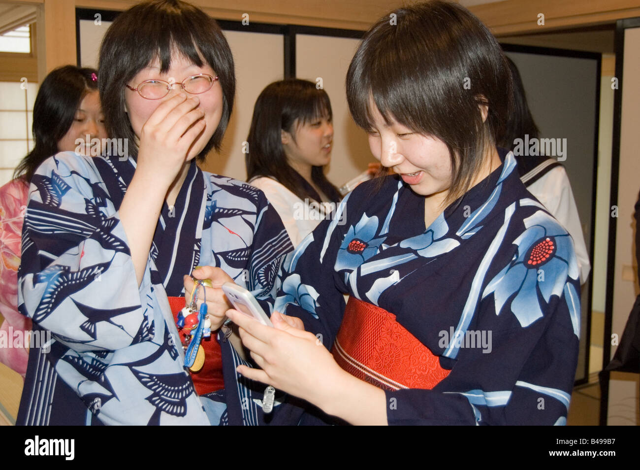 High school Japanese students laugh and look at photos on their cell ...