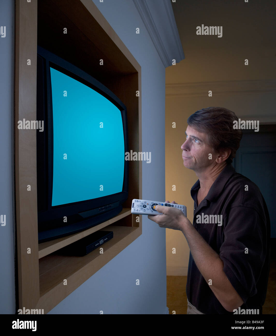 A middle aged man is very close to the TV and watching but looking ...