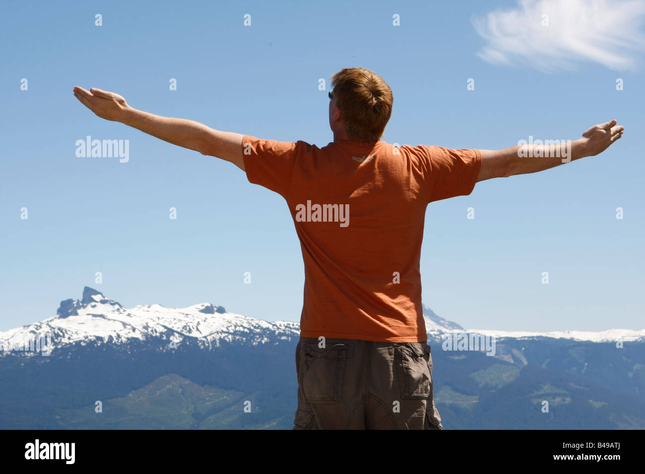 man stretching with arms wide open on top of a mountain in Whistler BC ...