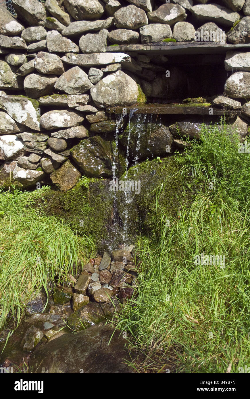 A lake district stream trickles through a grey slate wall Stock Photo ...