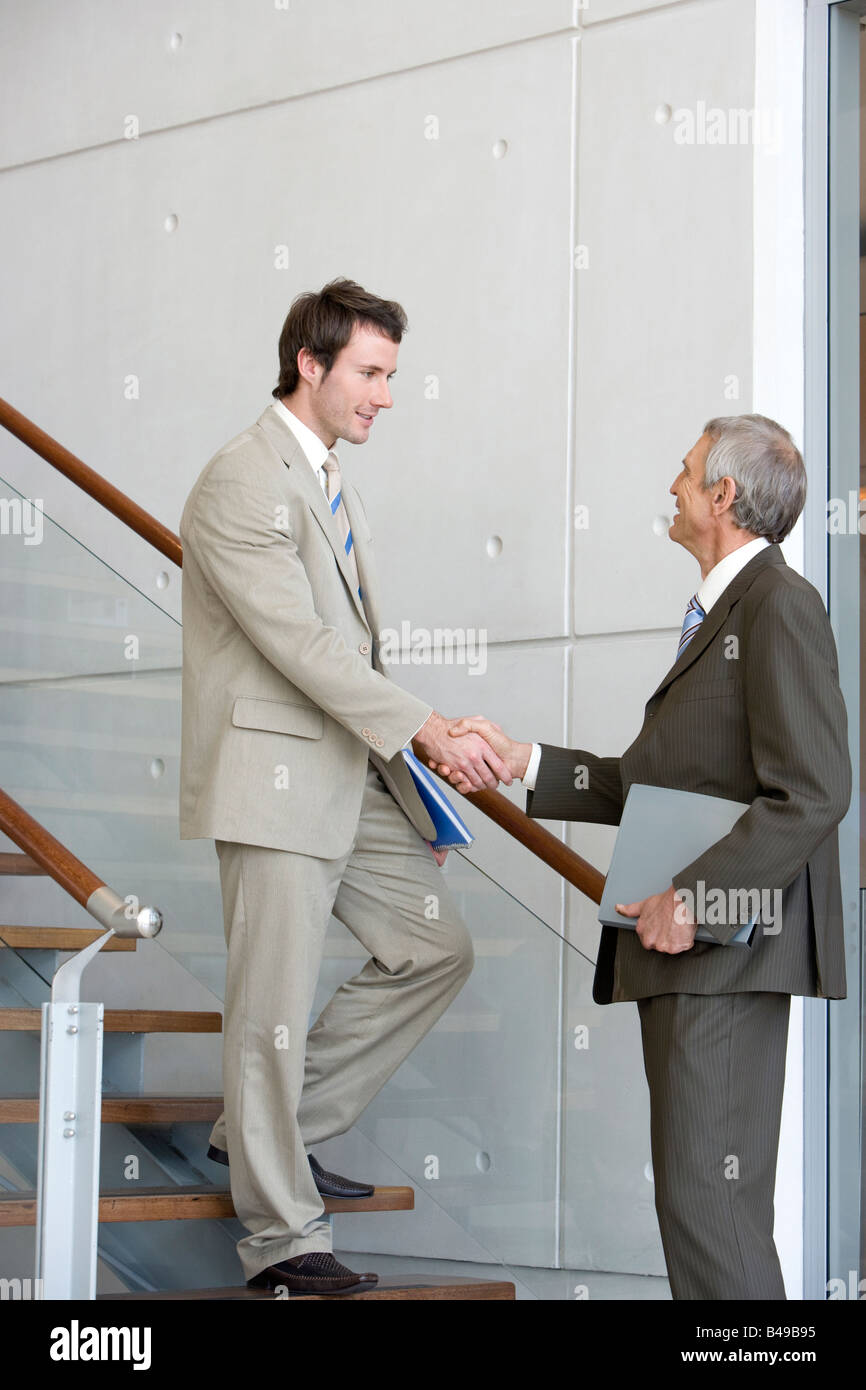 Businessmen shaking hands on steps Stock Photo - Alamy