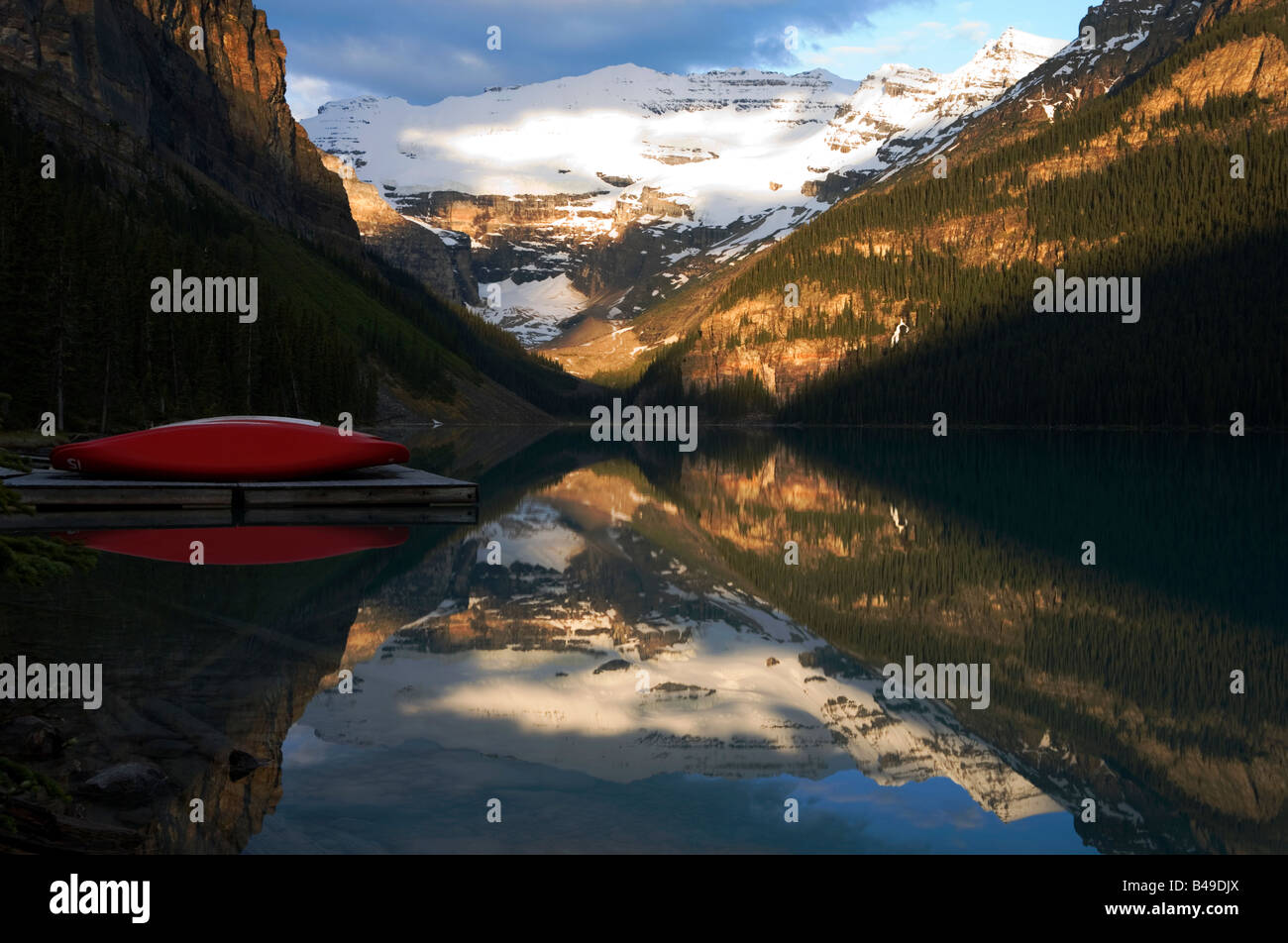 Red canoes and Victoria glacier reflecting in Lake Louise at sunrise ...