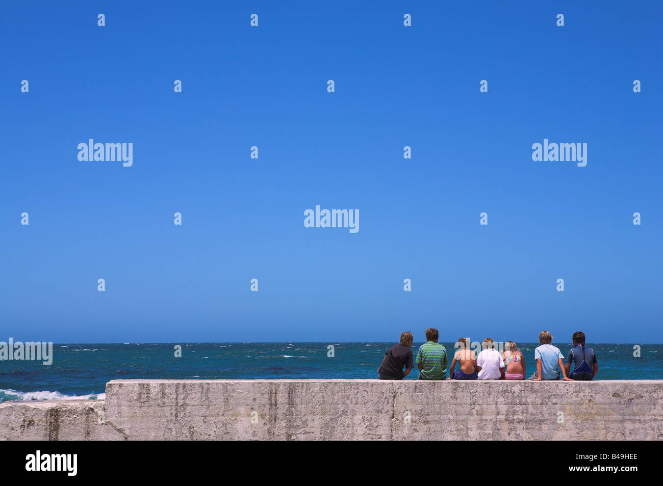 Seven friends sitting together on the harbor breakwater wall Stock ...