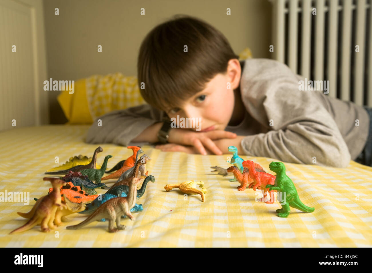 A pre-teen boy gazes over a horde of colorful plastic dinosaurs ...