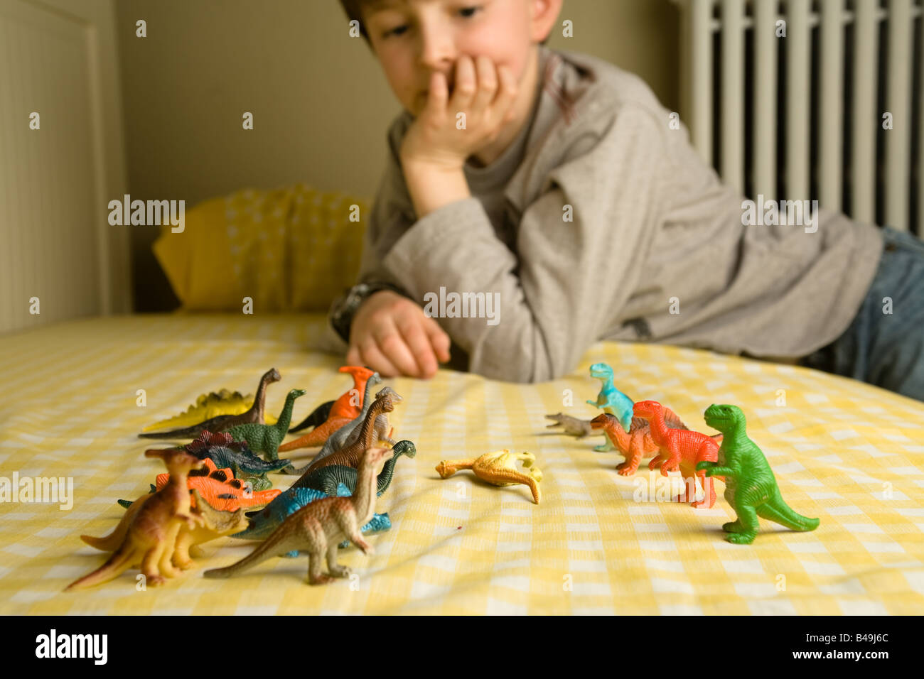 A pre-teen boy gazes over a horde of colorful plastic dinosaurs ...