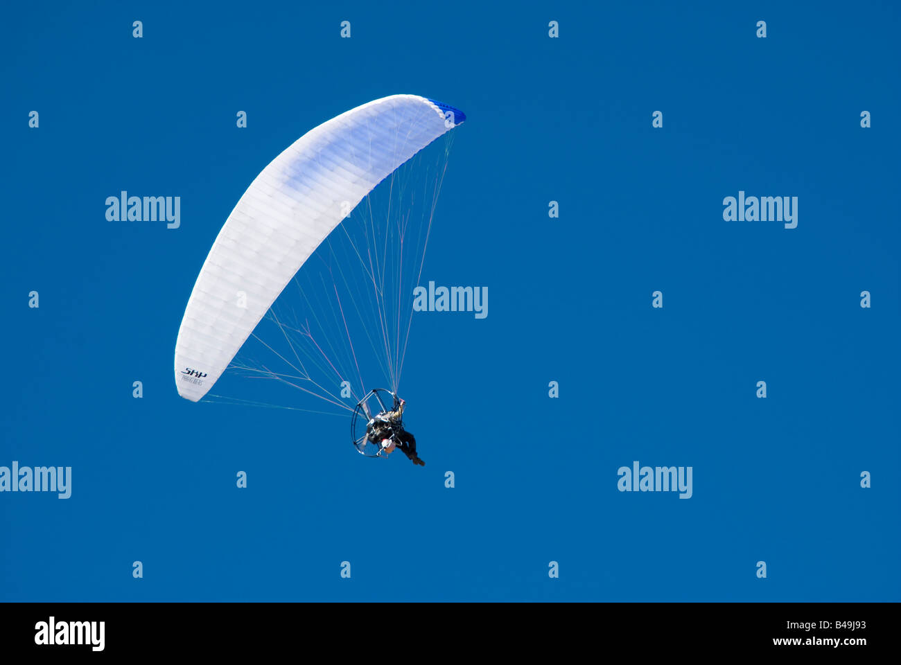 a powered paragliders in flight against a clear blue sky Stock Photo ...