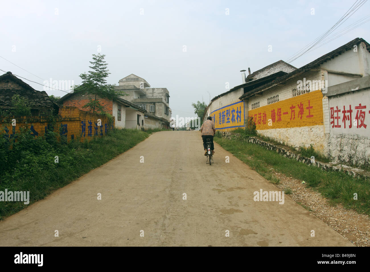 Peasant Woman riding bicycle alone up dirt street in rural Southwestern ...