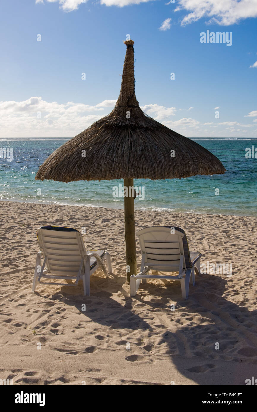 A straw umbrella over 2 beach chairs in Mauritius Stock Photo - Alamy