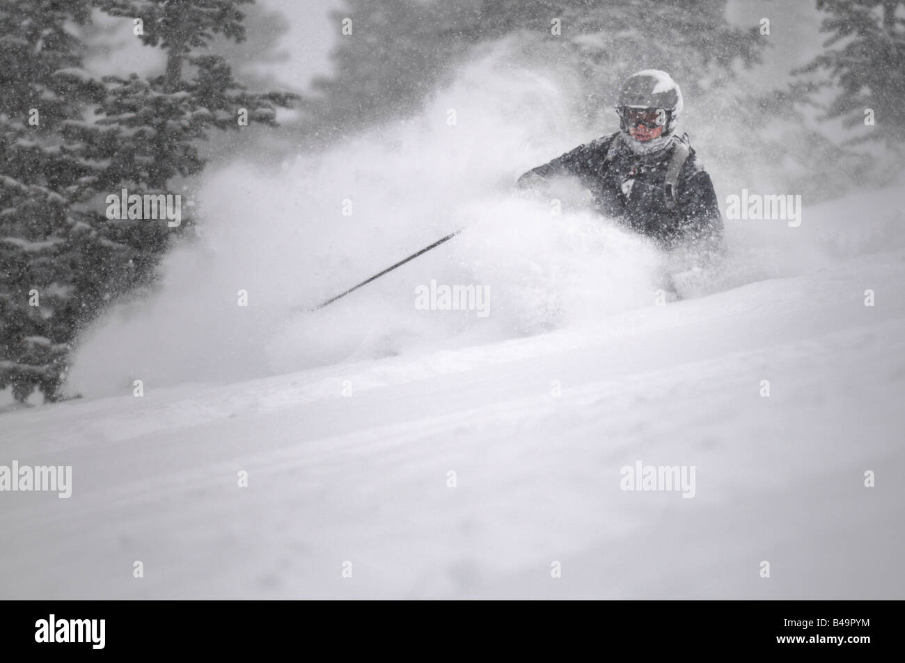 A skier in deep powder with a large spray of snow during a snow storm ...