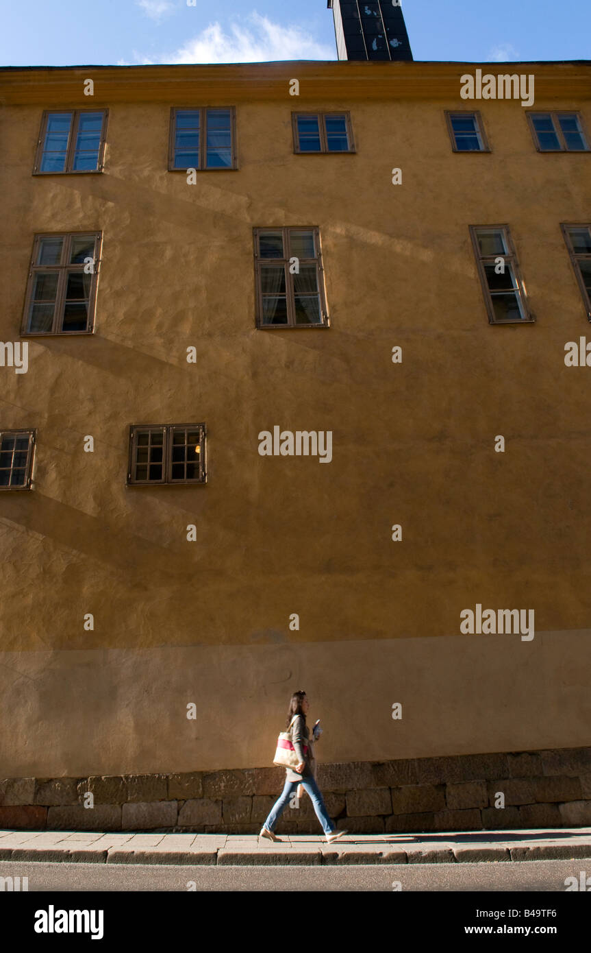 Young lady walking past building Stock Photo - Alamy