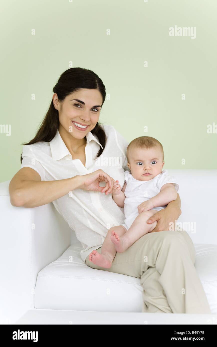 Woman holding baby on her lap, smiling at camera Stock Photo - Alamy