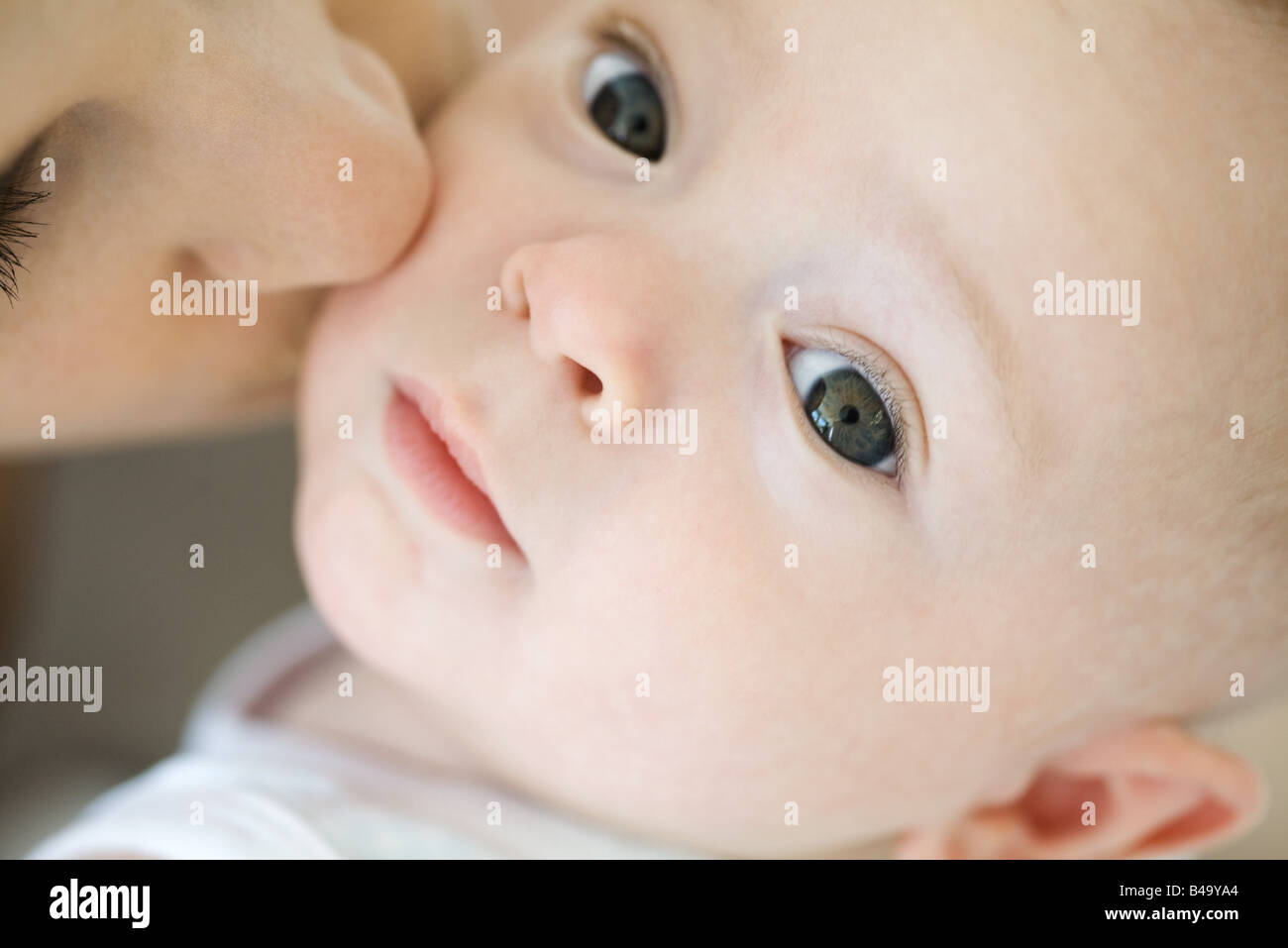Infant looking at camera, mother kissing cheek, cropped Stock Photo - Alamy