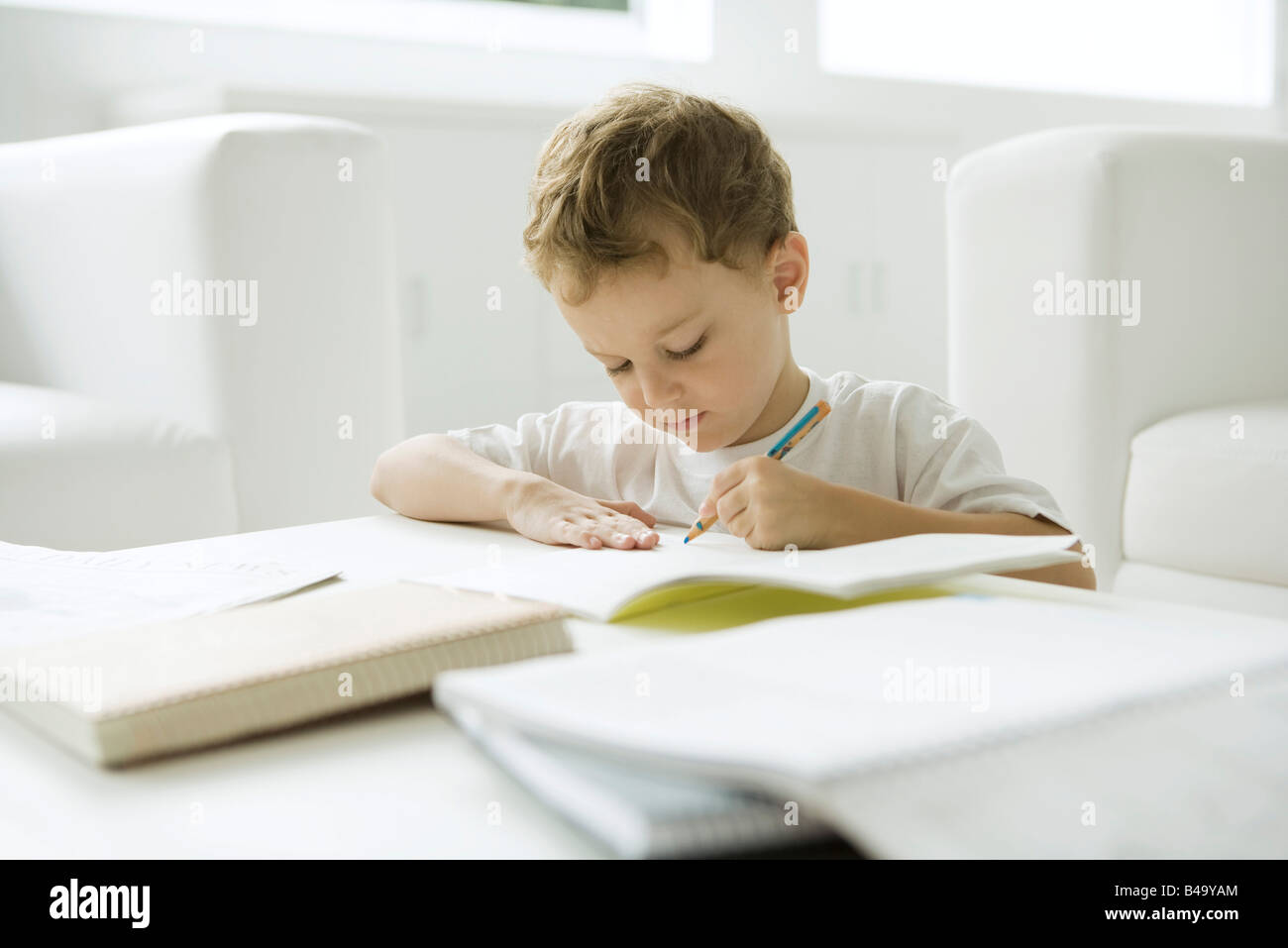 Little boy sitting at coffee table, working on homework Stock Photo - Alamy