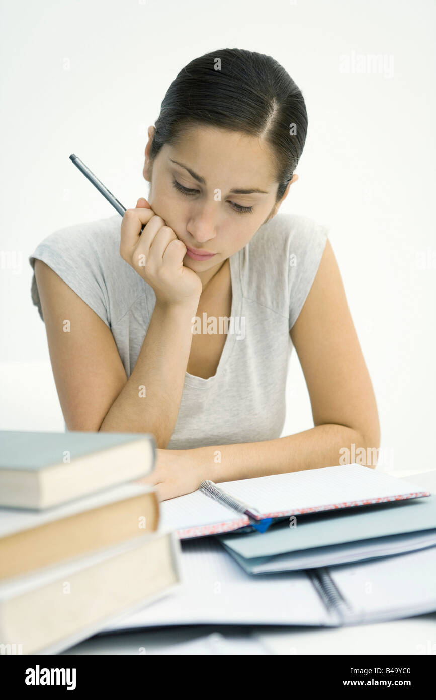 Young woman sitting with stack of books, studying notebook Stock Photo ...