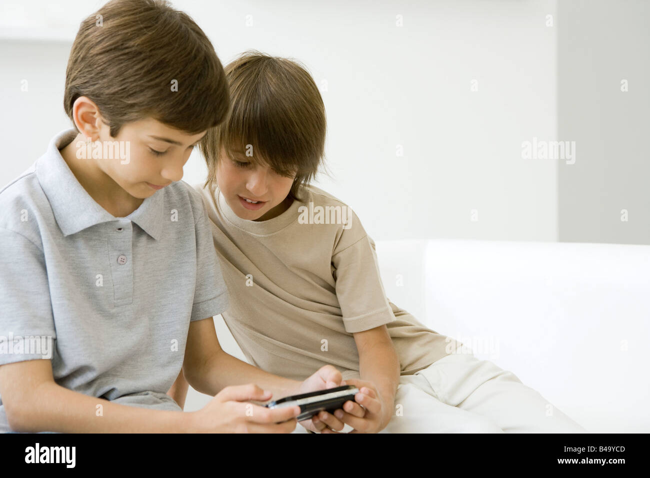 Two boys playing handheld video game together Stock Photo - Alamy