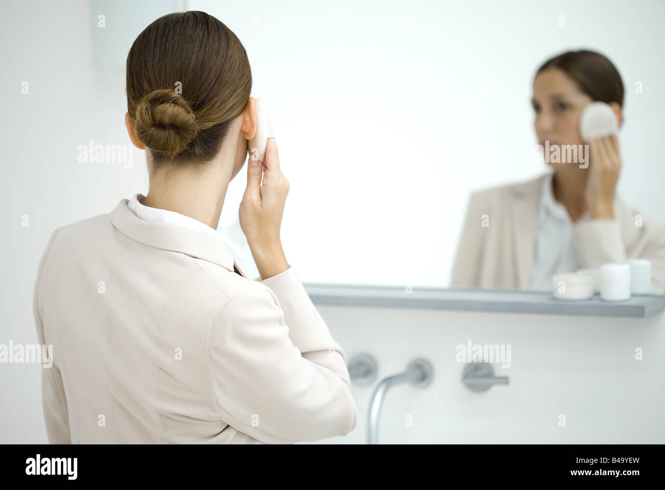 Professional woman powdering face in mirror, rear view Stock Photo - Alamy