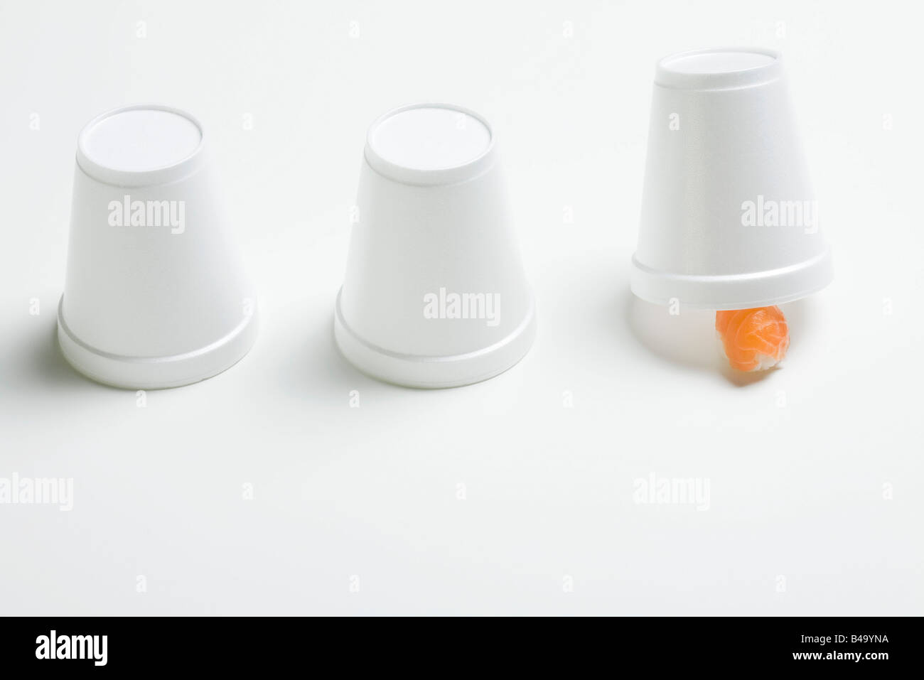 Three disposable cups in row, end cup lifted revealing single piece of ...