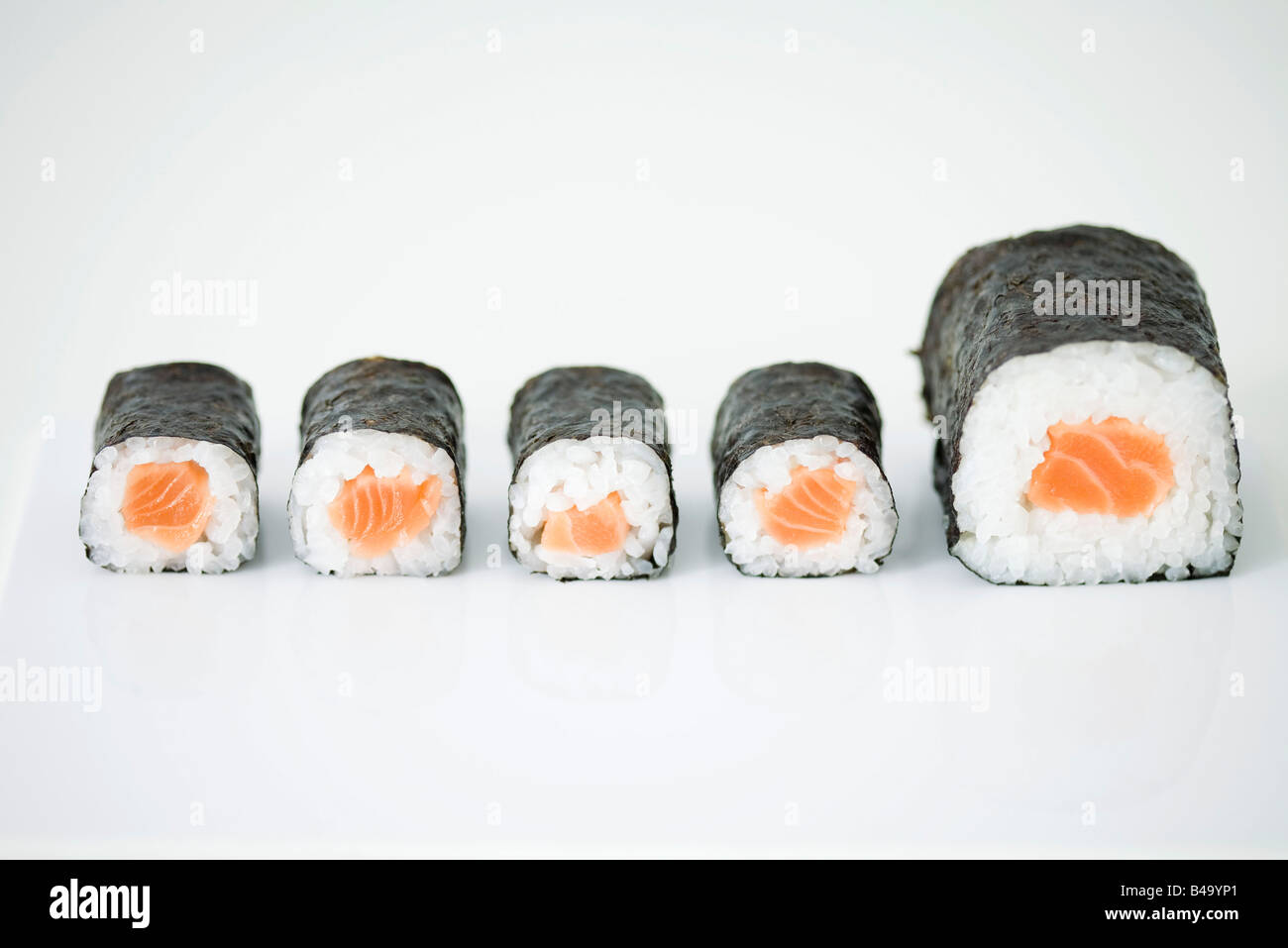 Five pieces of maki sushi arranged in row, end piece larger than others ...