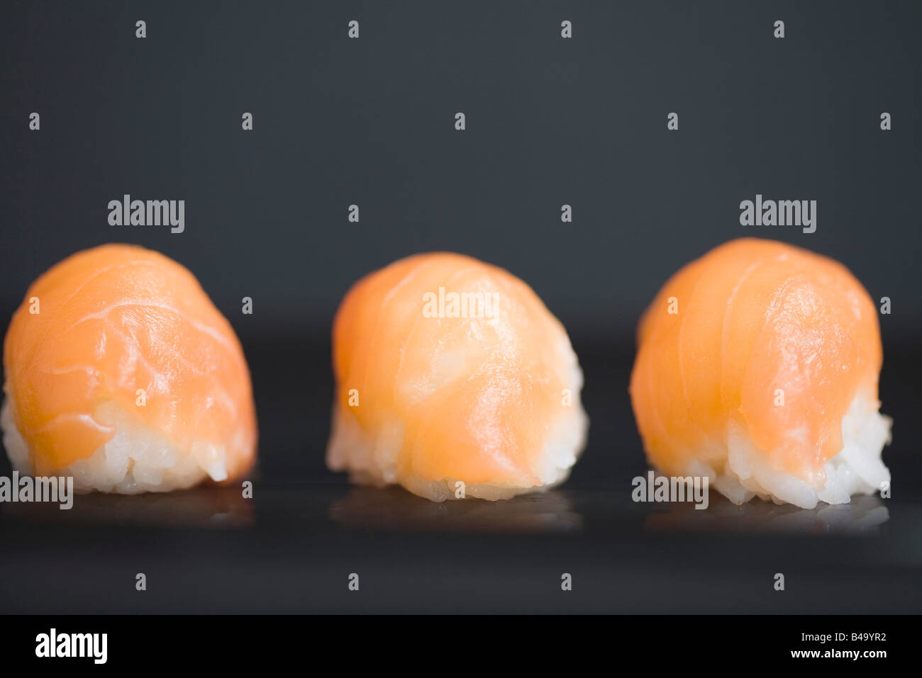 Three pieces of salmon nigiri sushi with dark background, close-up ...