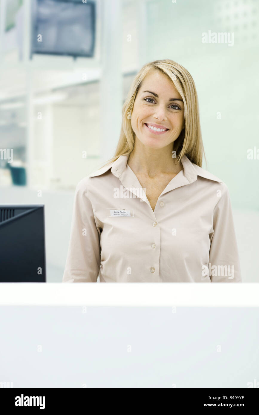Businesswoman standing behind counter, smiling at camera, portrait ...