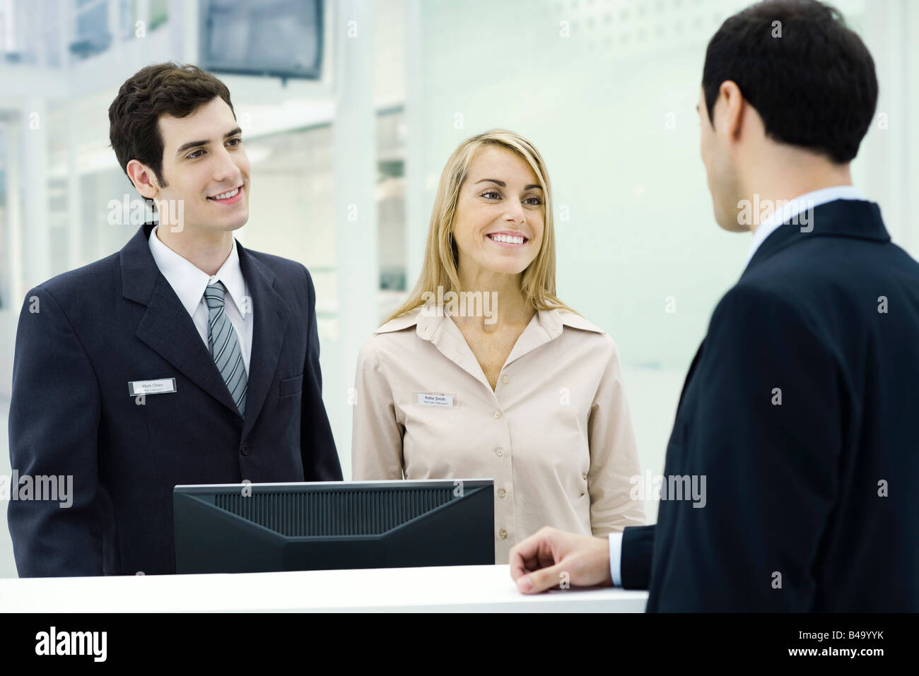 Customer service representatives smiling at businessman waiting at ...