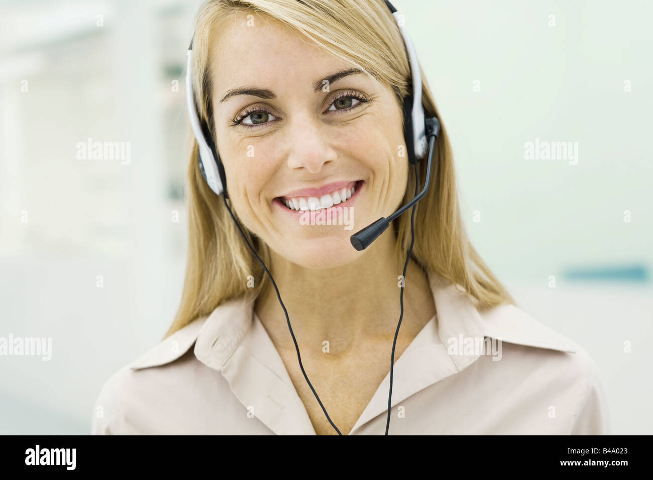 Woman wearing headset, smiling at camera, portrait Stock Photo - Alamy