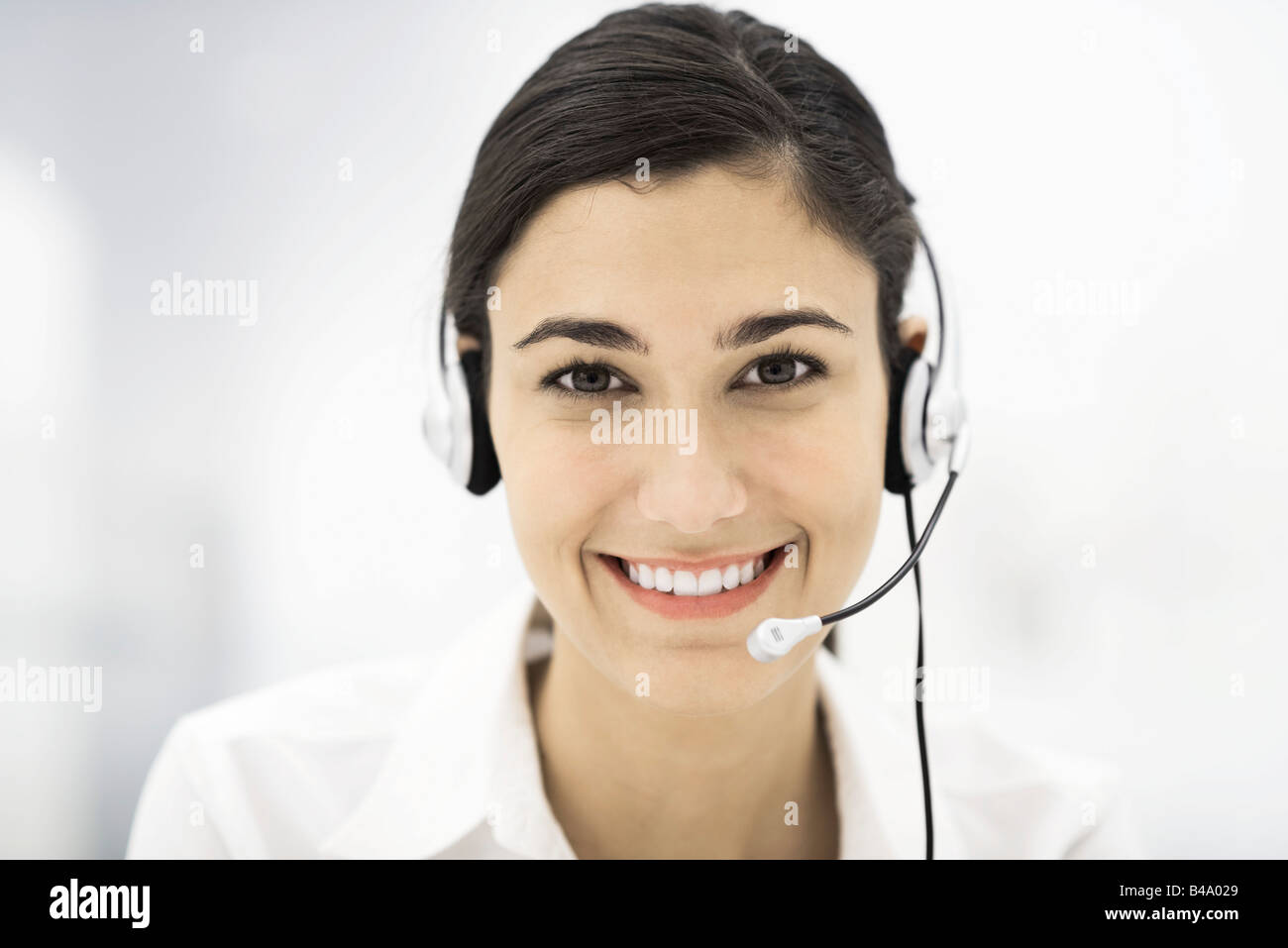 Woman wearing headset, smiling at camera, portrait Stock Photo - Alamy