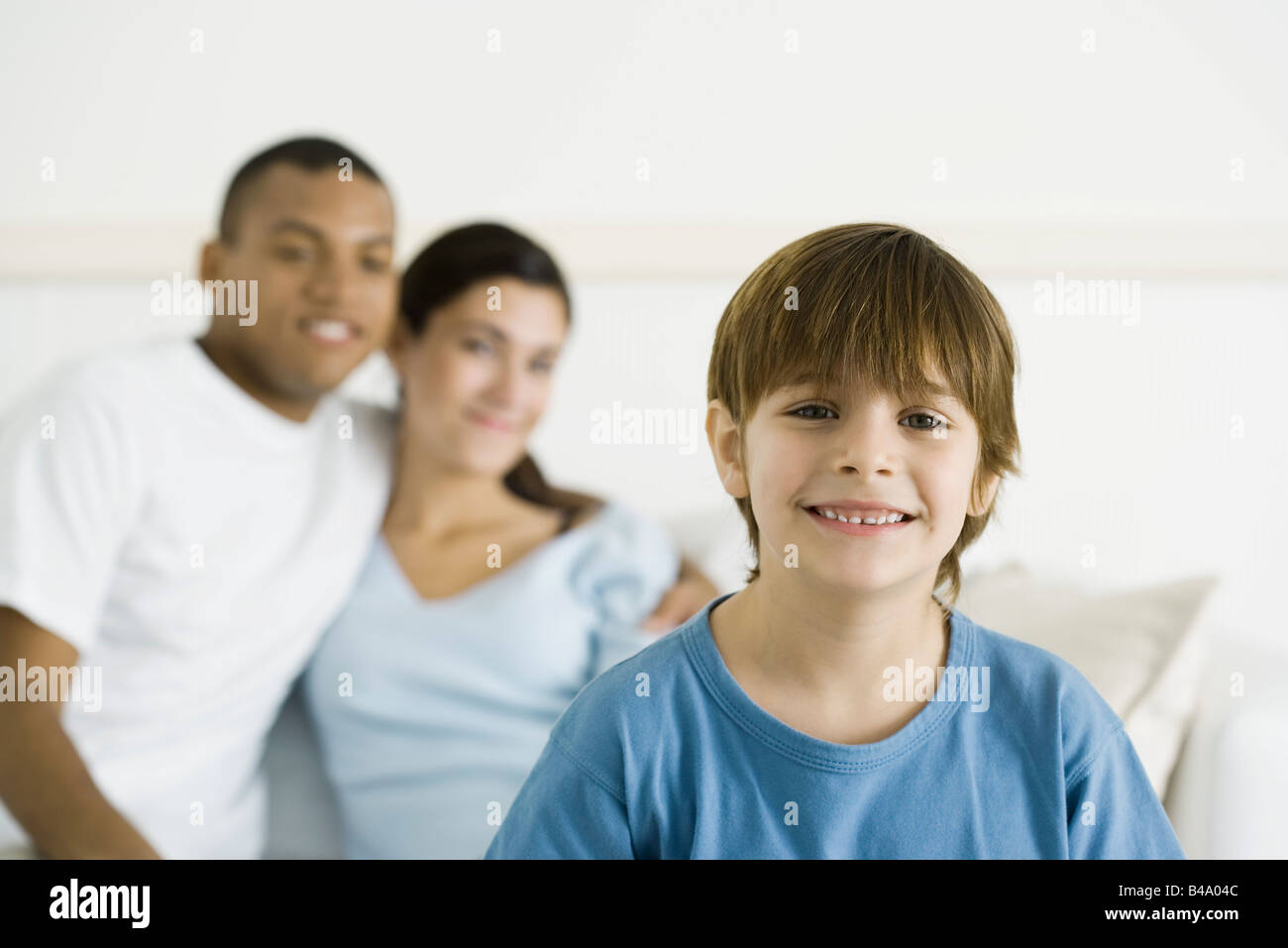 Boy smiling at camera, parents sitting in background Stock Photo - Alamy
