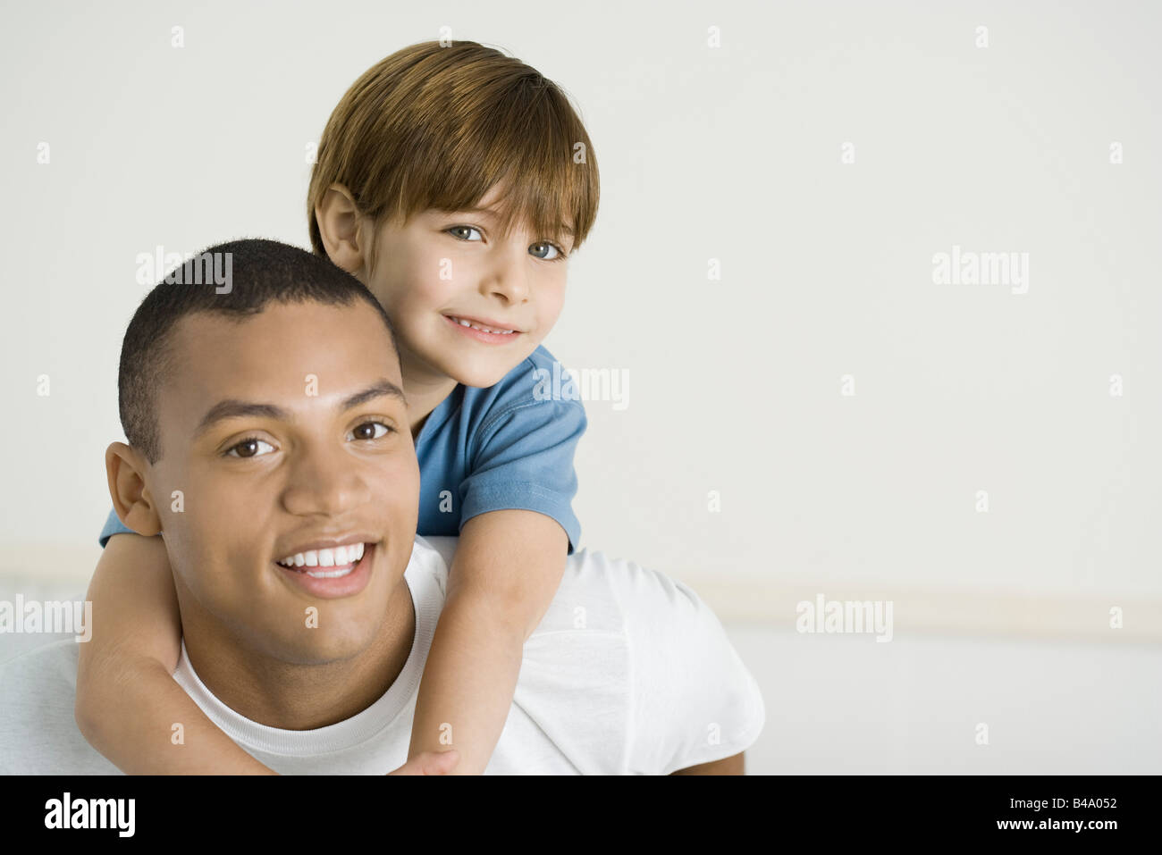 Boy leaning over father's shoulders, both smiling, portrait Stock Photo ...