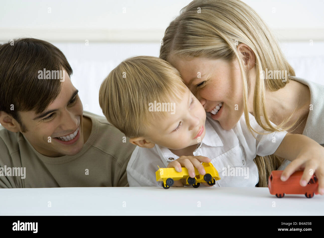 Little boy sitting with parents, playing with toy trucks, mother ...