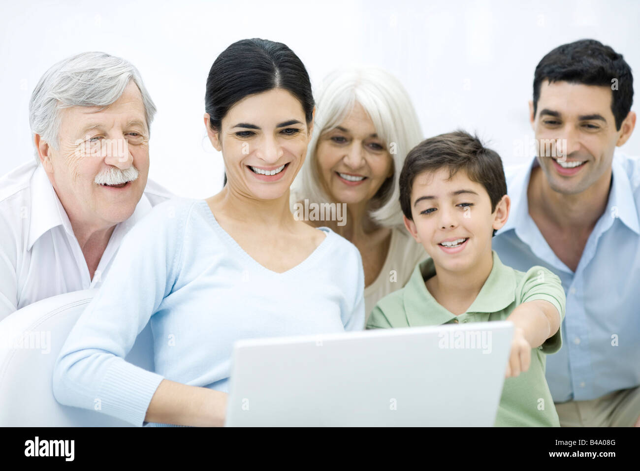 Multi-generation family gathered around laptop computer, smiling Stock ...