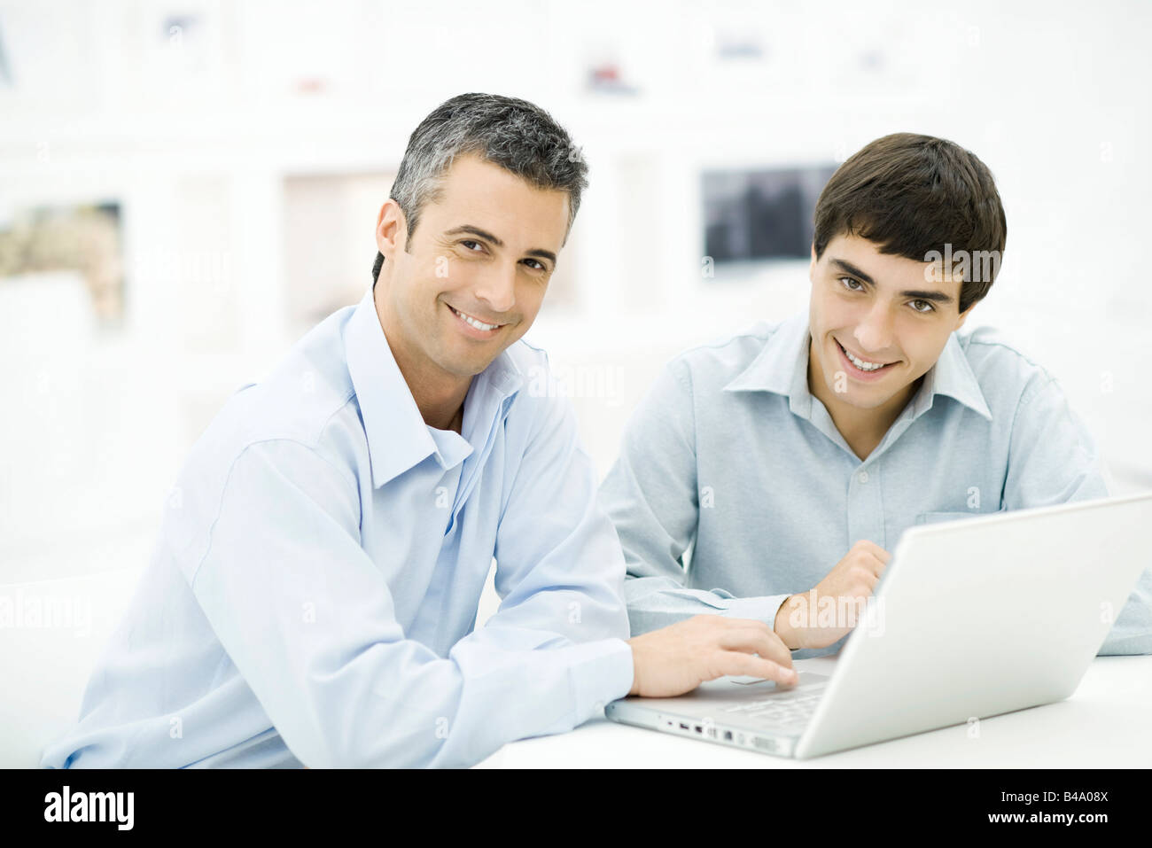 Two men using laptop computer together, both smiling at camera Stock ...