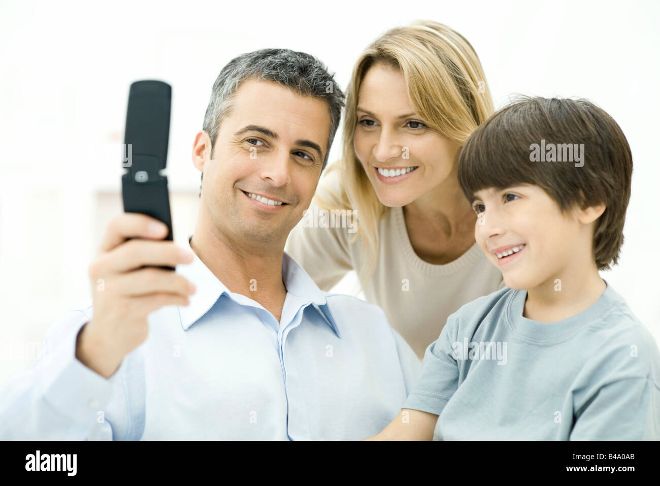 Family looking at cell phone together, smiling Stock Photo - Alamy