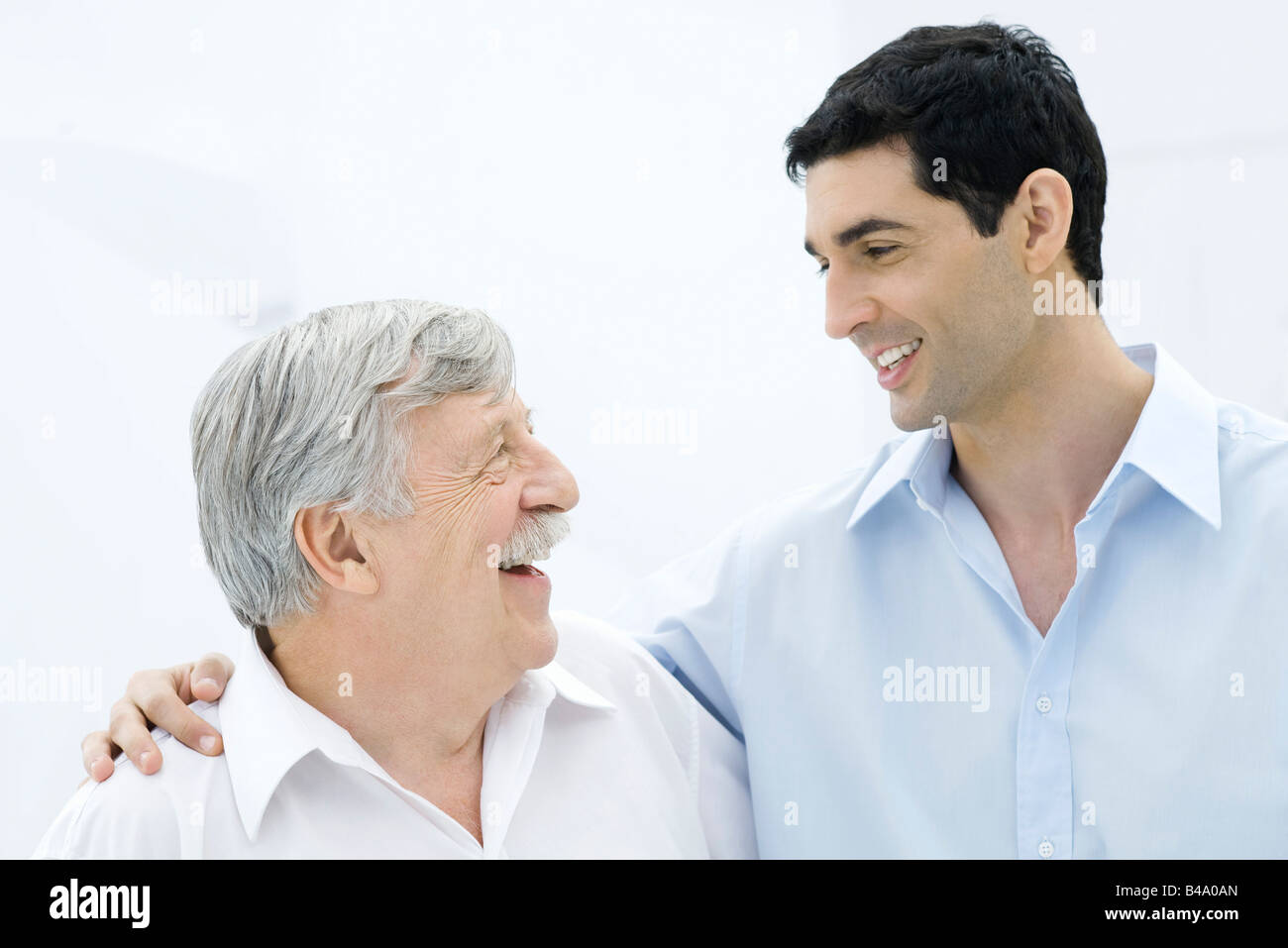 Adult son with arm around father's shoulder, both smiling at one ...