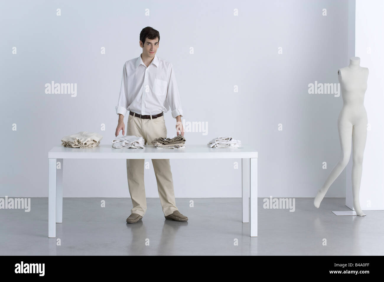 Man standing beside table with folded clothing, smiling at camera Stock ...