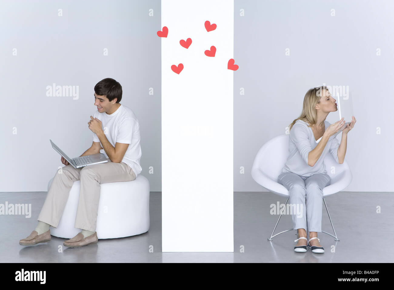 Woman kissing laptop computer, man looking at his own laptop and ...