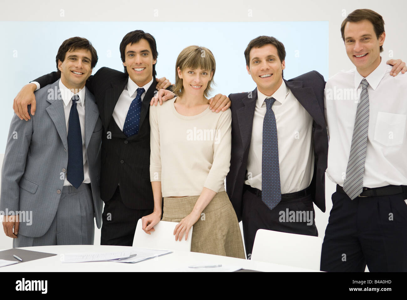 Business team standing with arms around each other's shoulders, smiling ...