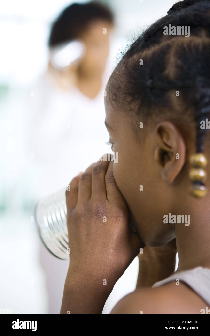 Girl talking through tin can phone Stock Photo - Alamy