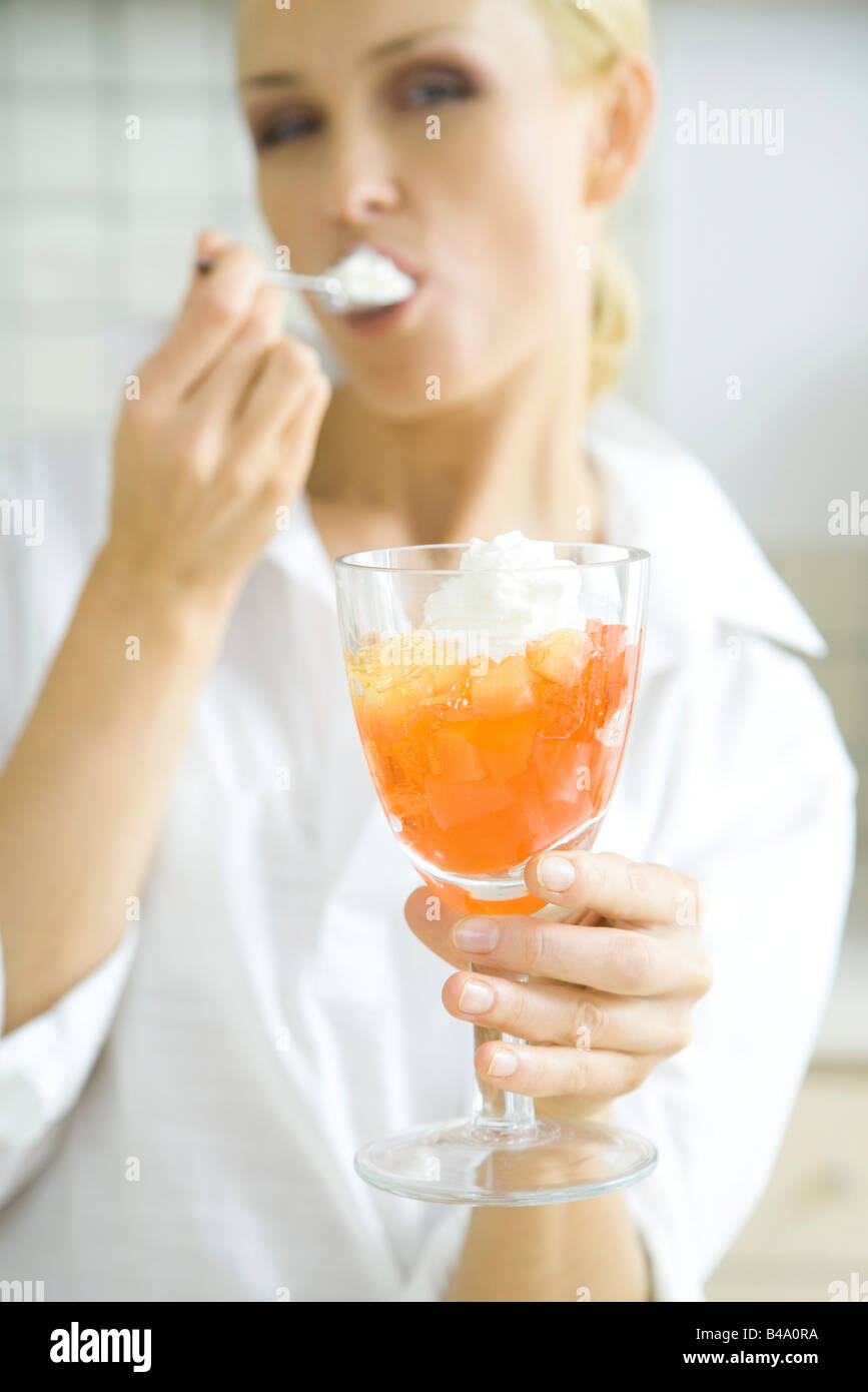 Woman eating jellied fruit dessert with whipped cream Stock Photo - Alamy