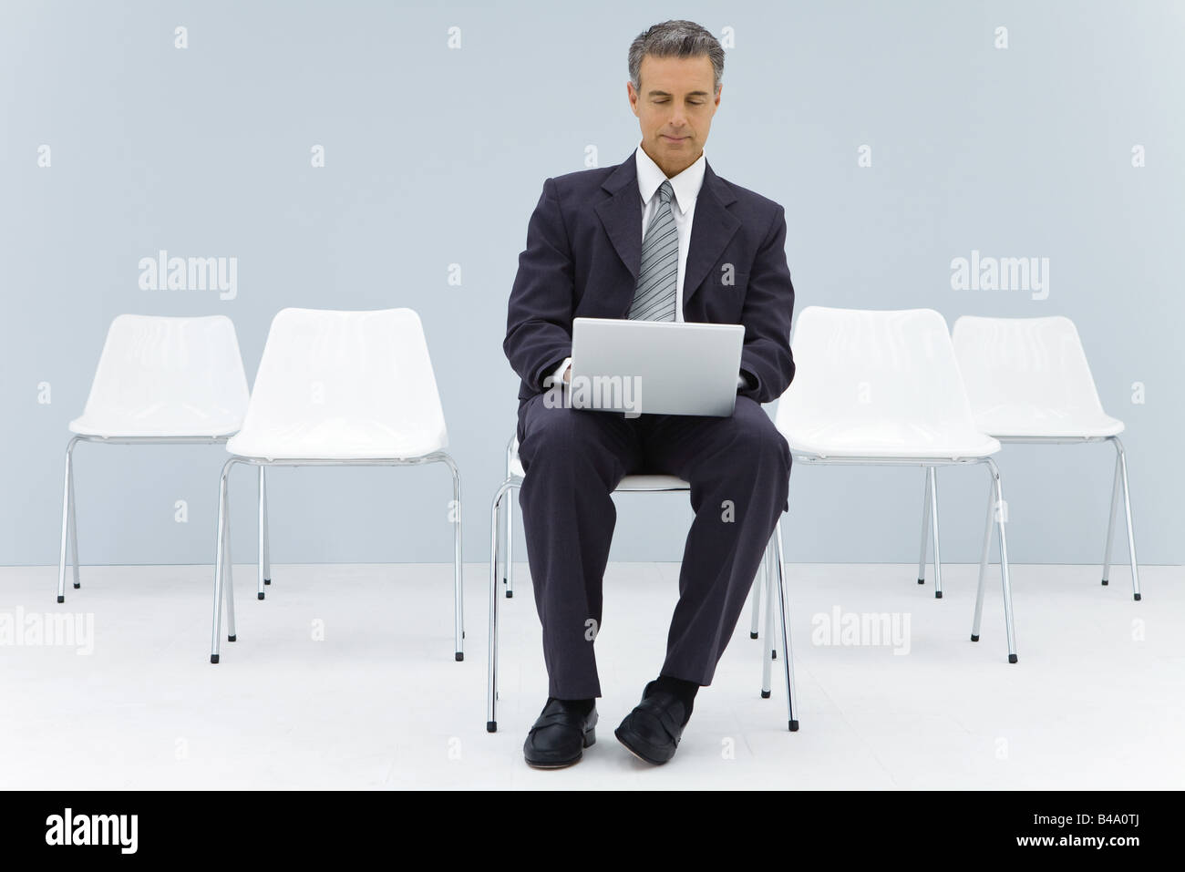 Business man sitting alone in room using laptop computer Stock Photo ...