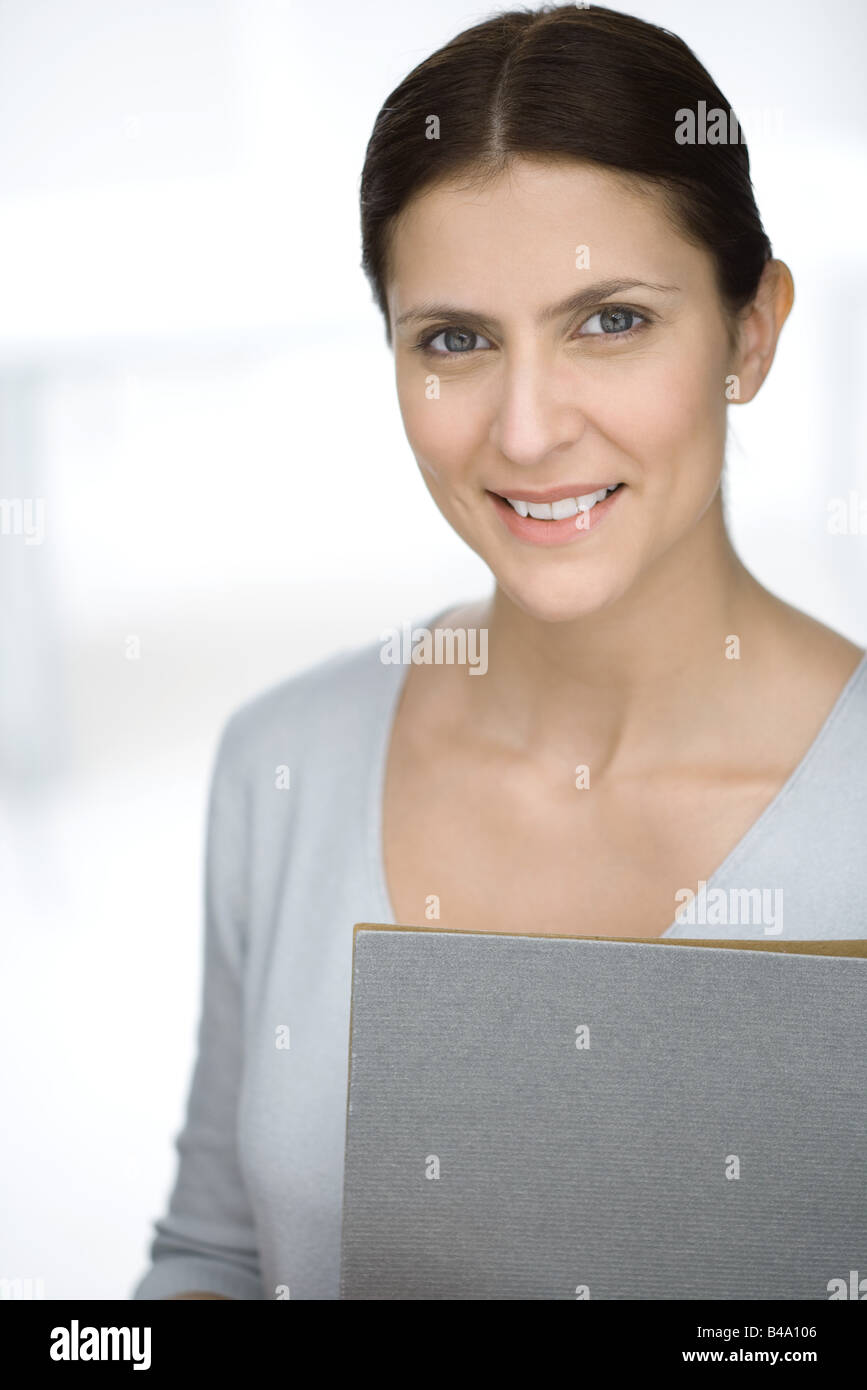 Woman holding folder, smiling at camera, portrait Stock Photo - Alamy
