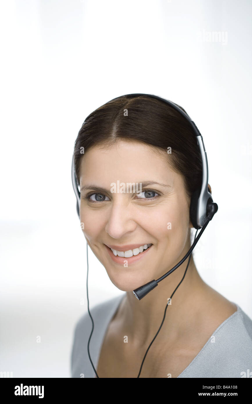 Woman wearing headset, smiling at camera, portrait Stock Photo - Alamy