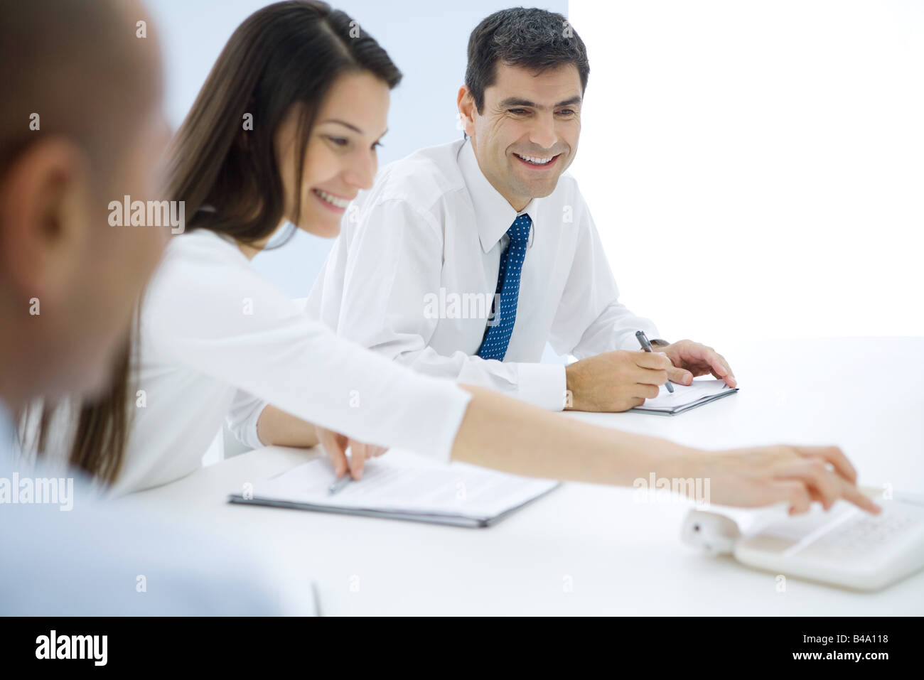 Professionals sitting at table, making conference call Stock Photo - Alamy