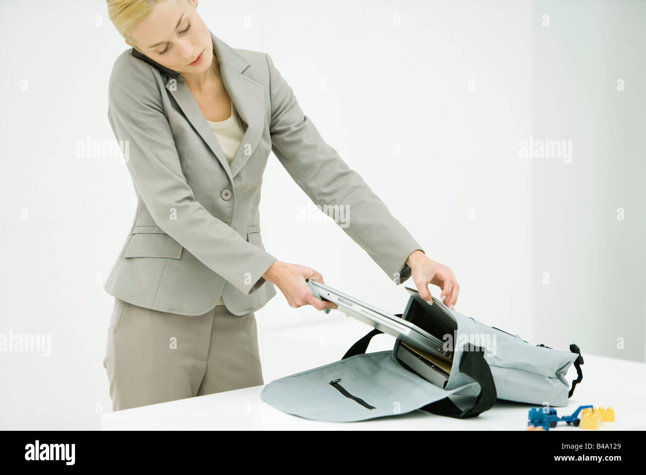 Professional woman using cell phone, putting laptop computer in ...