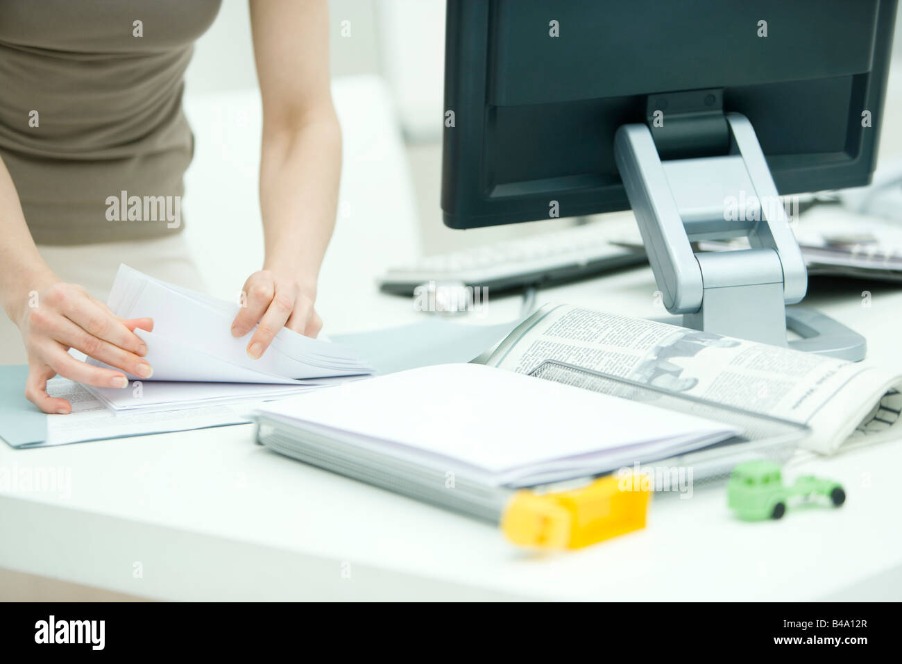 Woman sorting through documents on desk, child's toys in foreground ...