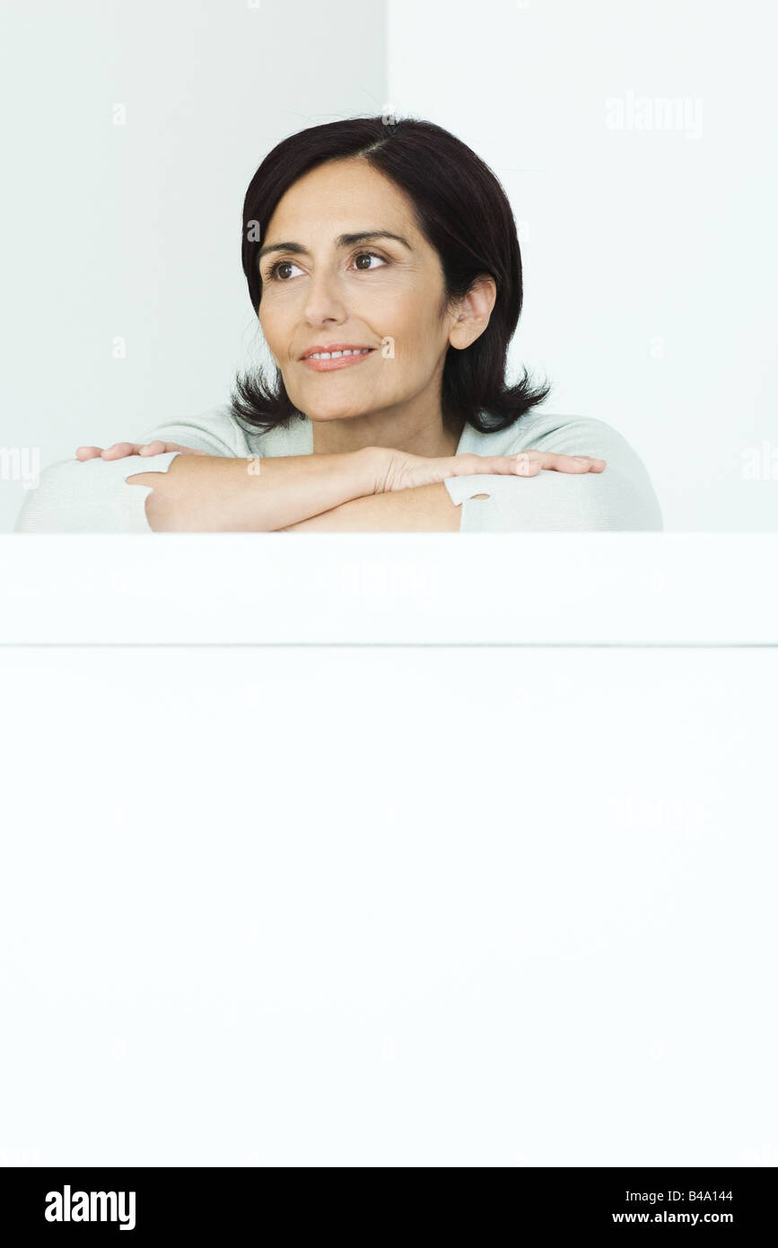 Woman leaning against ledge, arms folded, portrait Stock Photo - Alamy