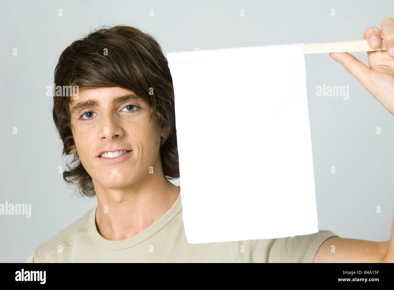 Young man holding up white flag, smiling at camera Stock Photo - Alamy