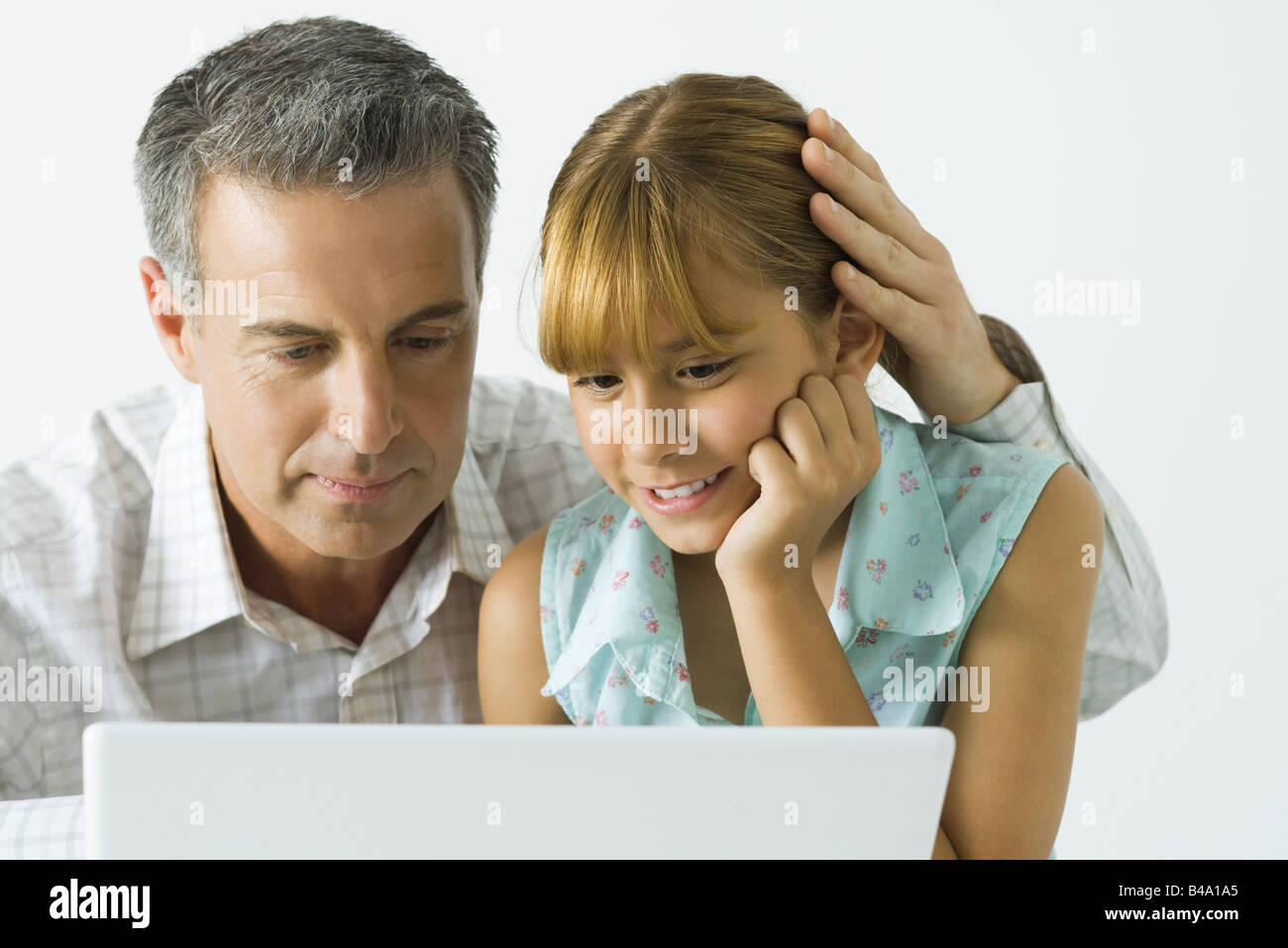 Father and daughter looking at laptop computer together, man's hand on ...