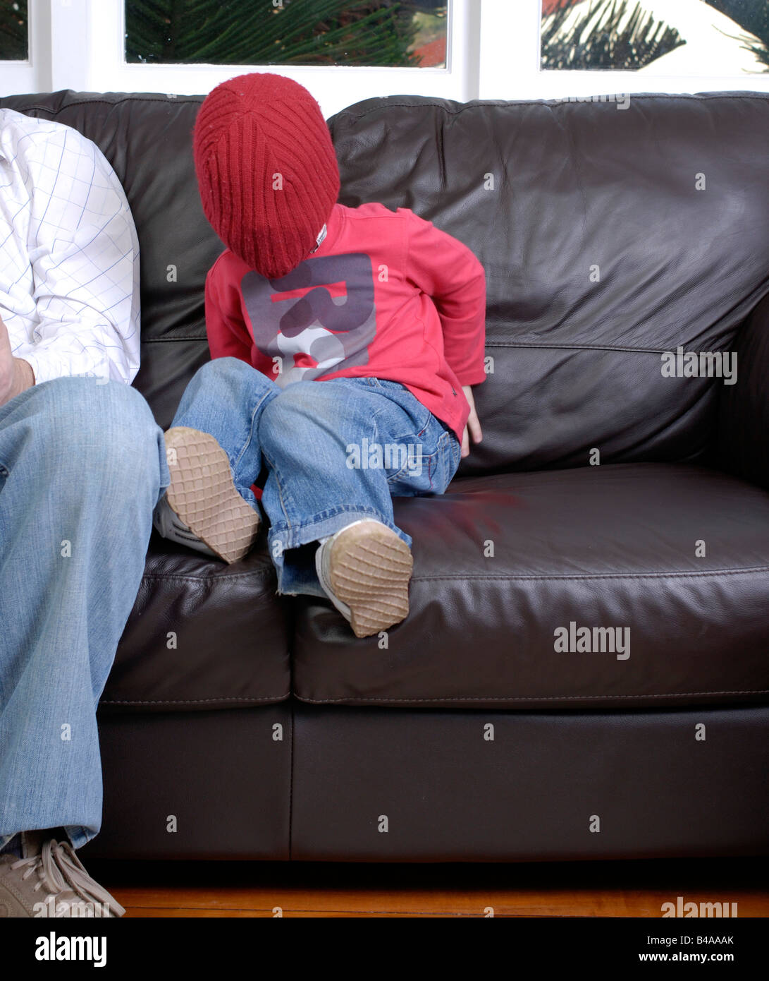 A young boy concealing his face with a woolen hat pulled down over his ...