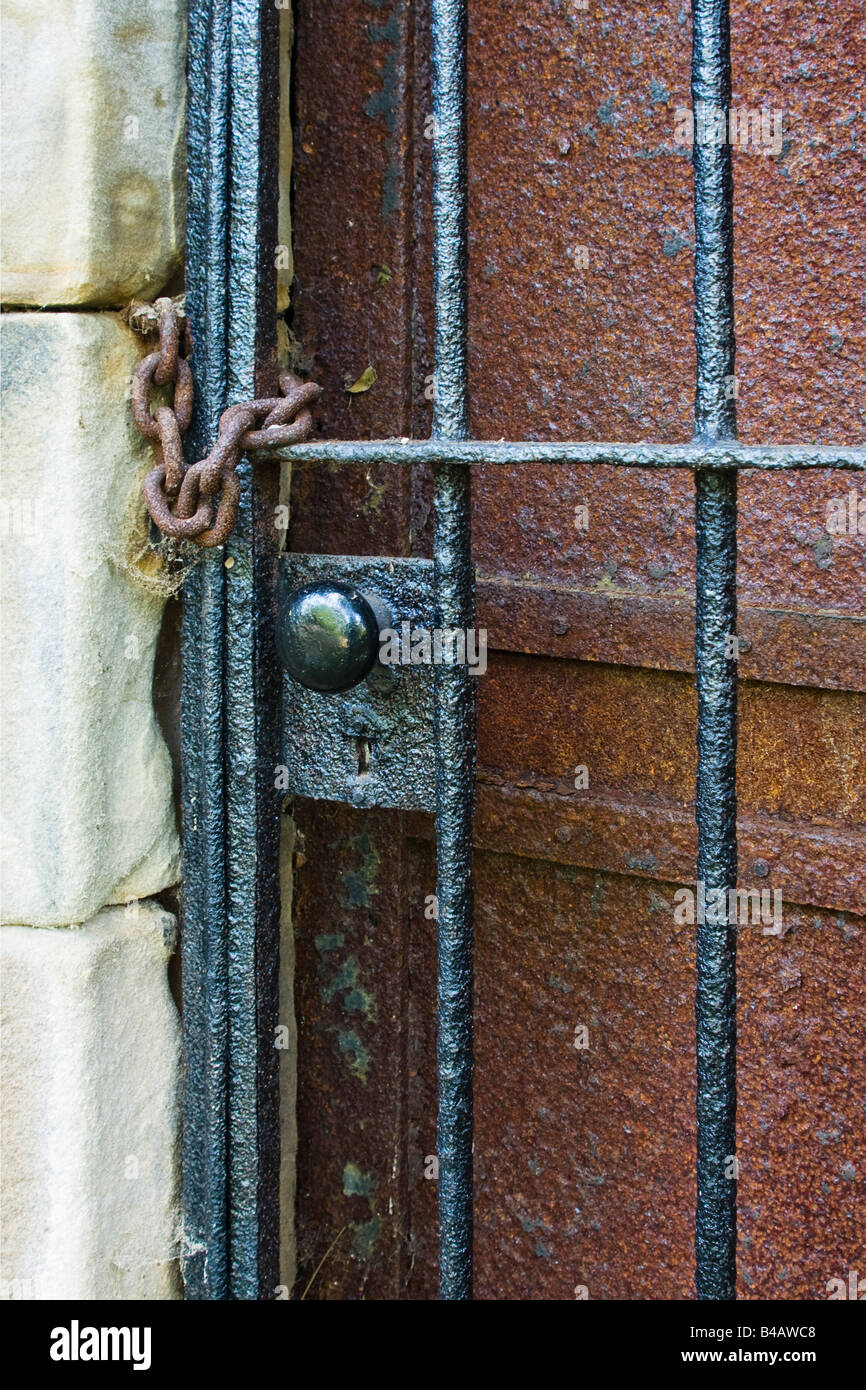 Rusty locked door to a crypt protected with a door of black bars locked ...